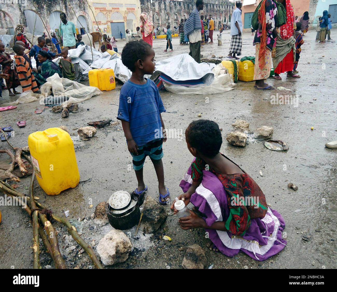 A young Somali girl from southern Somalia, cooks food in rain outside a ...