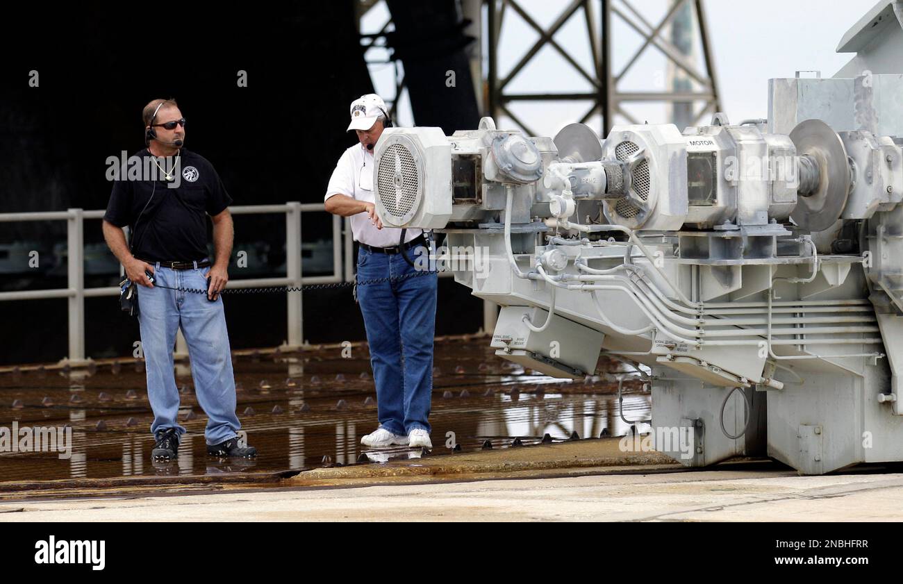 Workers monitor the movement of the rotating service structure as it is ...