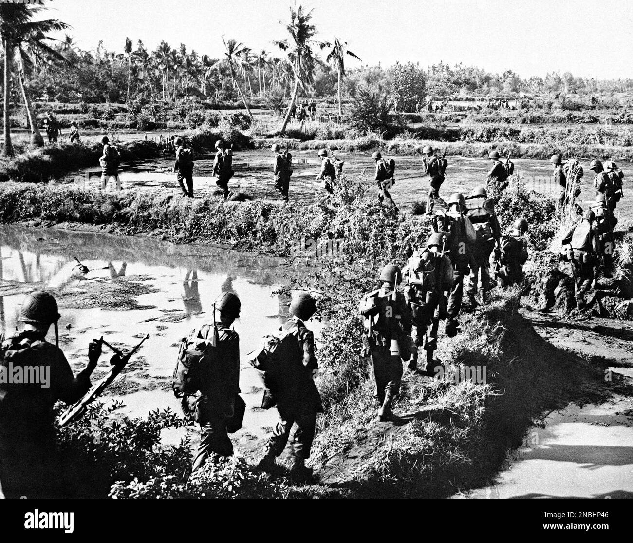 American soldiers skirt rice paddies on Luzon island in the Philippines ...