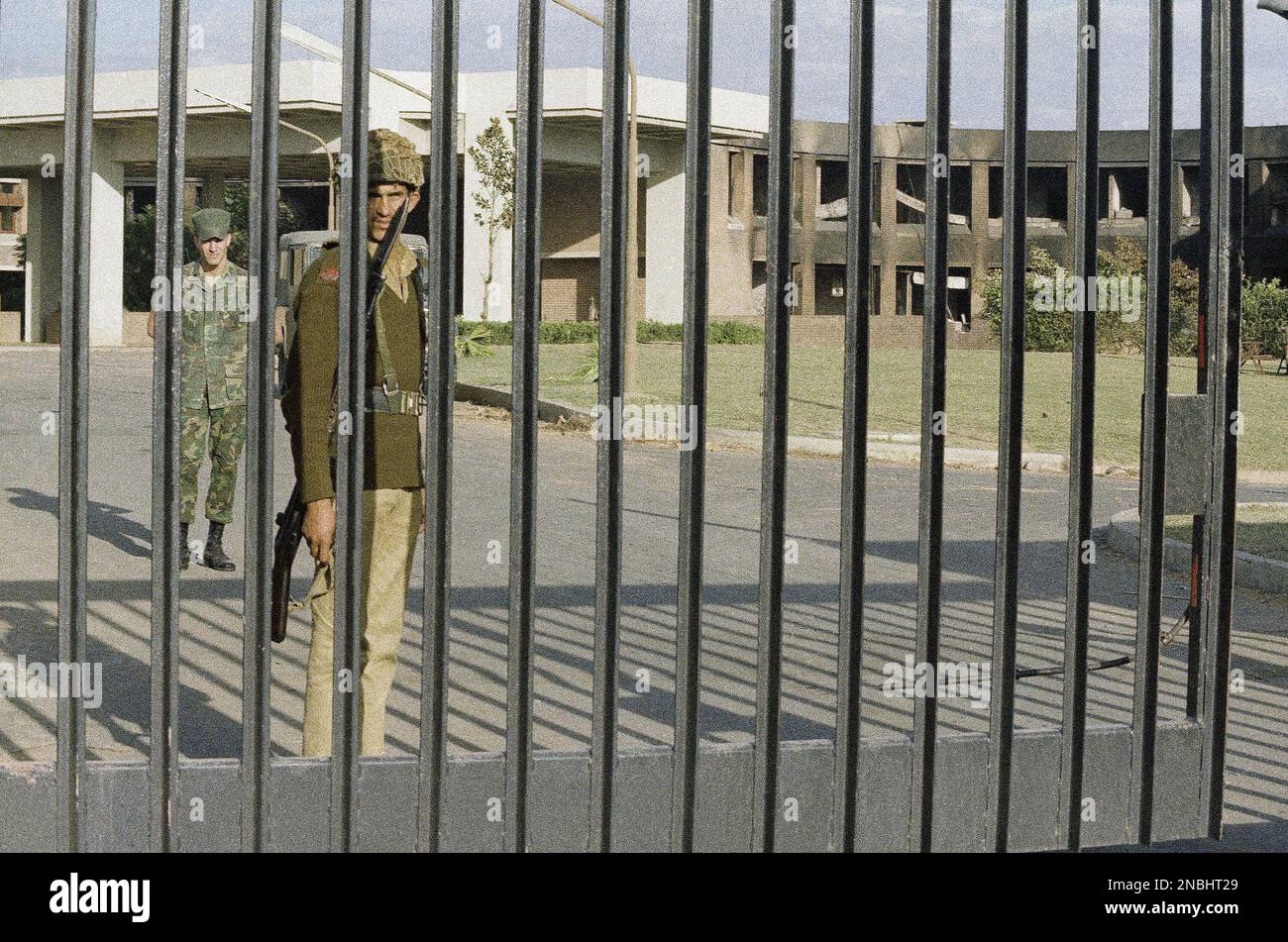 Guards stand inside the gates of burned out buildings in Islamabad ...