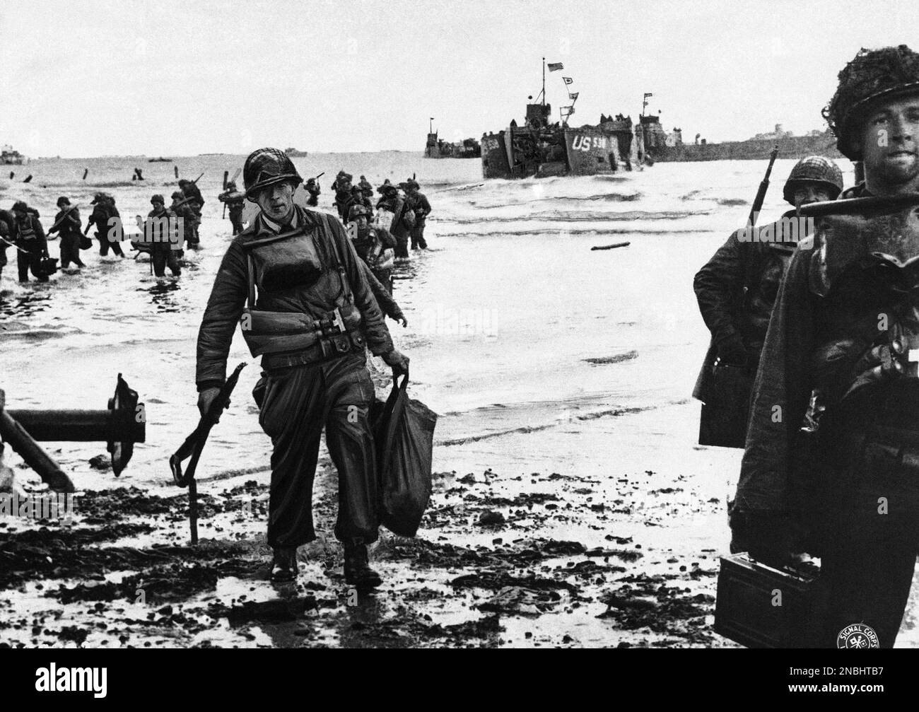 U.S. assault troops, laden with equipment, wade through the surf to a ...