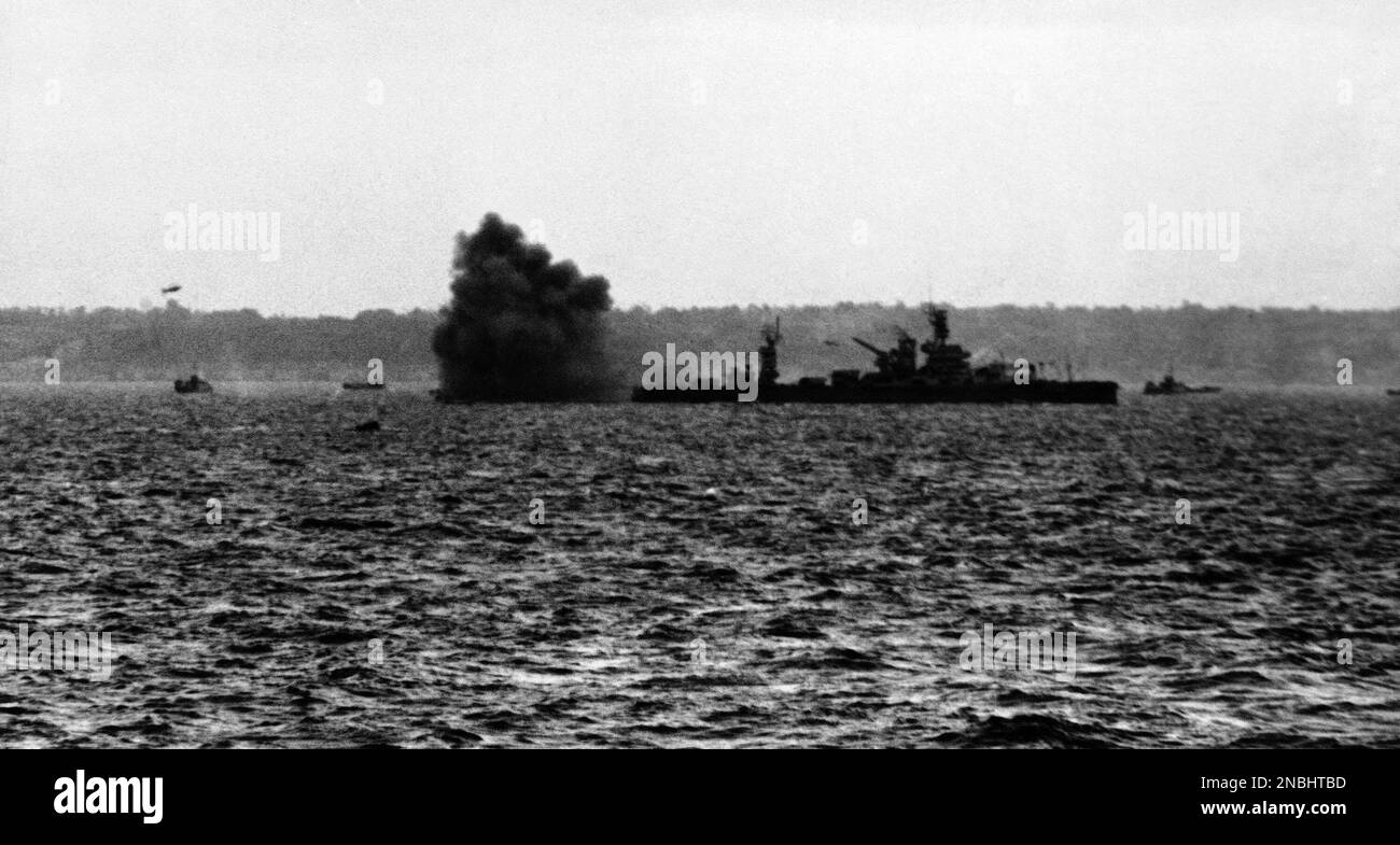 A puff of black smoke blows away from the guns of the USS Arkansas in ...
