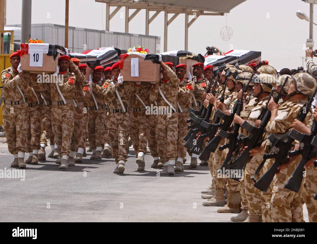 Iraqi Army soldiers carry the remains of 32 Iraqi soldiers who were ...