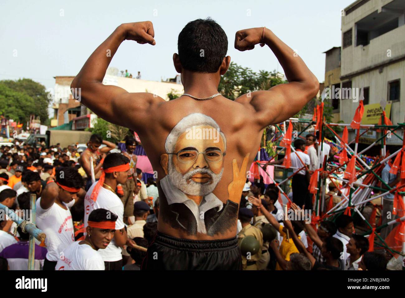 An Indian man flexes his muscles as an image of Gujarat Chief Minister ...