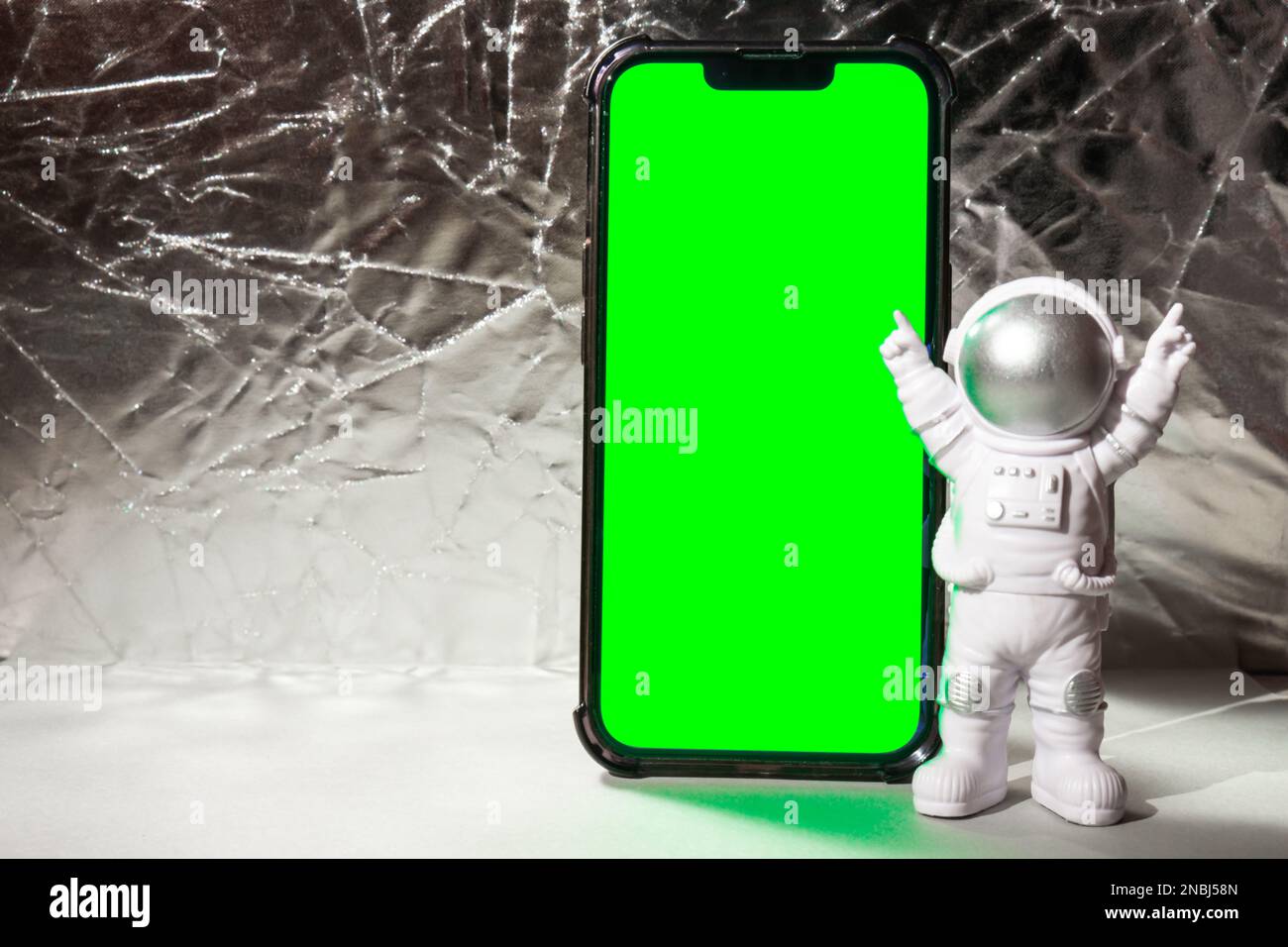 Plastic toy figure astronaut with mobile phone chroma key green screen ...