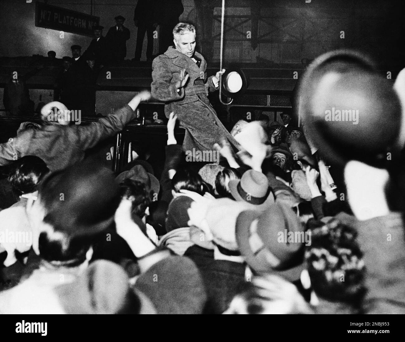 Actor Charlie Chaplin waving his acknowledgment to cheers greeting him ...