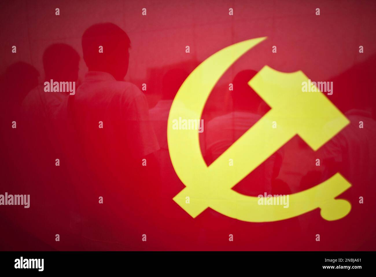 People, seen through a Chinese Communist Party flag, pose for photos ...