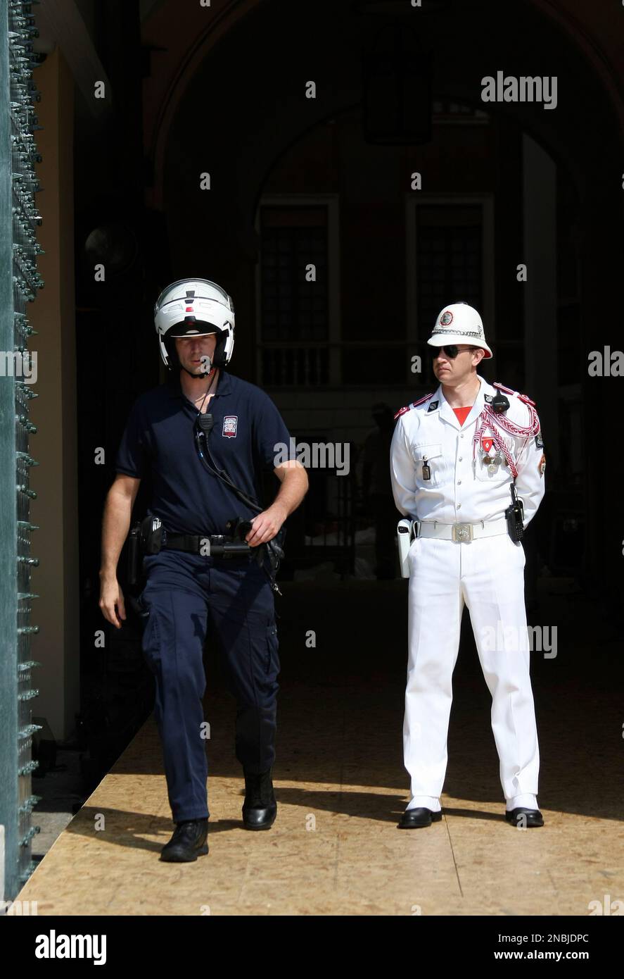 A guard watches a police officer leaving the Monaco Palace Thursday ...