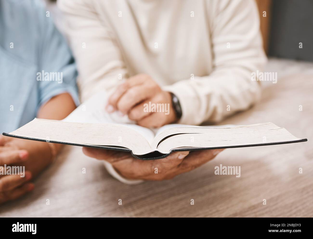 Hands, bible and prayer with a senior couple reading a book together in ...