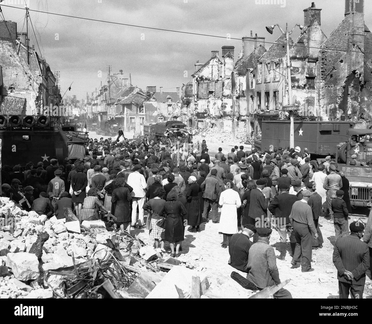 Civilians of the war battered town of Isigny, France, gather to hear an ...