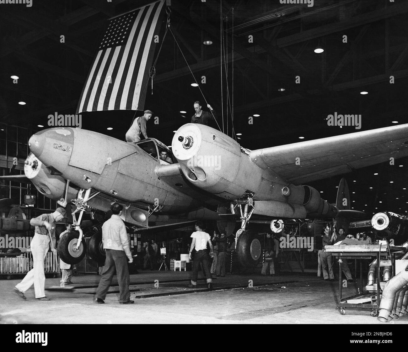 A new P-38 Lightning fighter is lifted off its rolling jig at the end ...