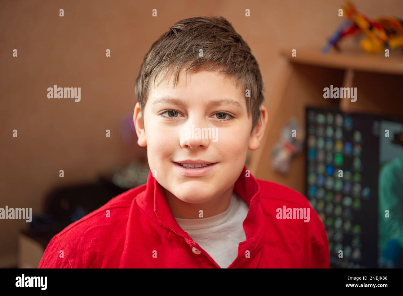 Close portrait of a smiling European teenage boy in a red shirt in his ...