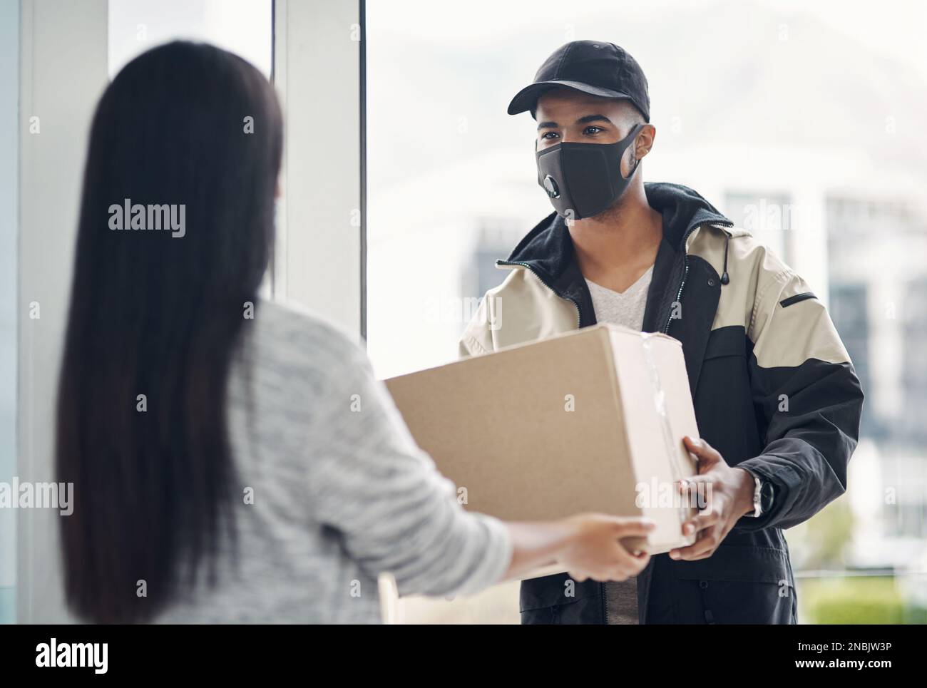 Keep yourself and your customers safe. a masked young woman receiving a ...