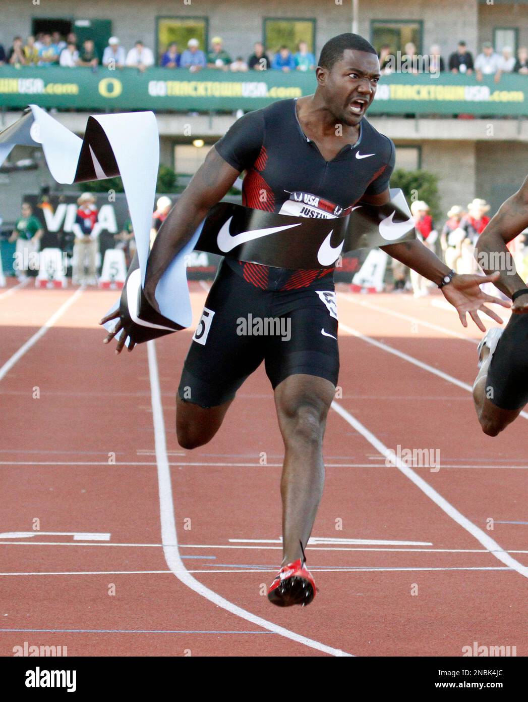 Sprinter Justin Gatlin hits the tape to finish second in the 100 meter ...