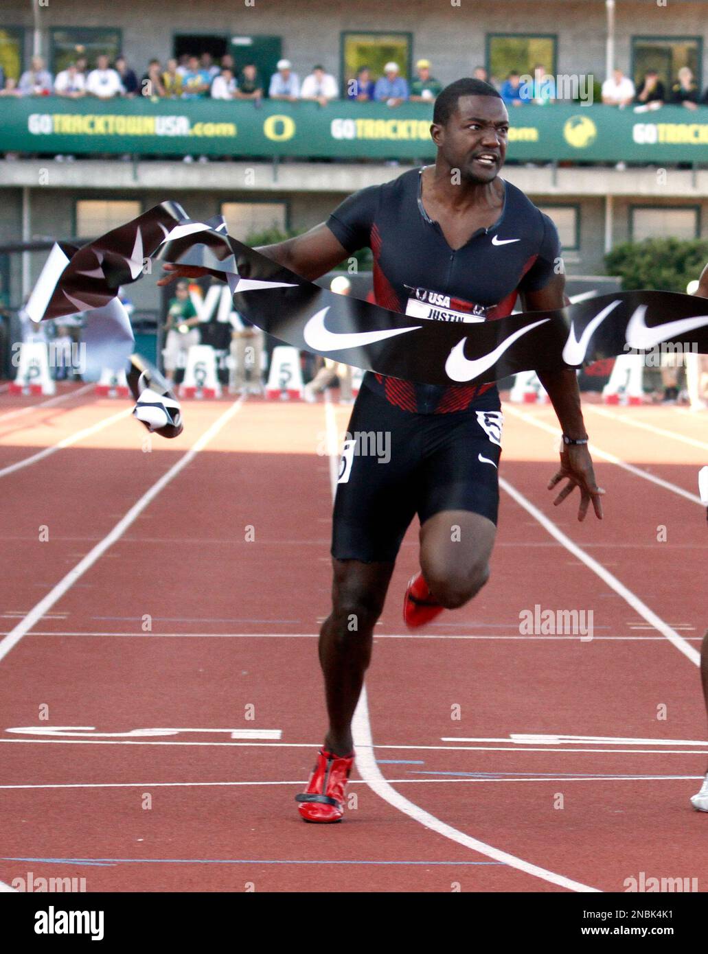 Sprinter Justin Gatlin hits the tape to finish second in the 100 meter ...