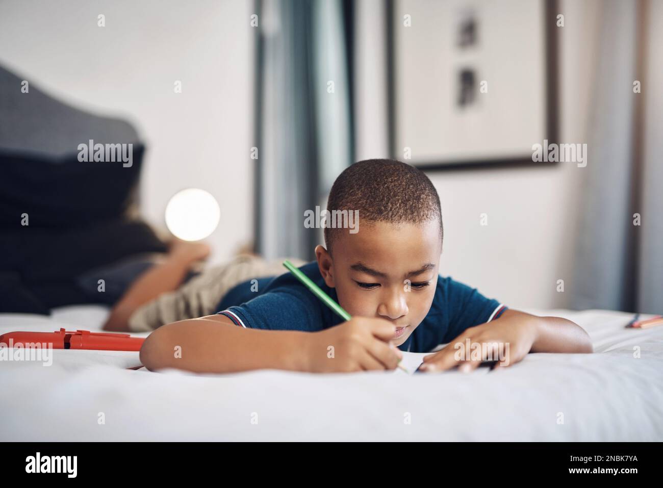 I like to write letters. a young boy using colouring pencils while ...