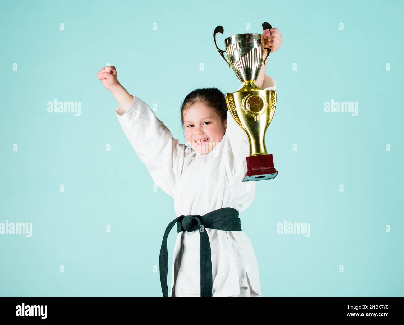small girl with champion cup. martial arts. winner little girl in gi ...