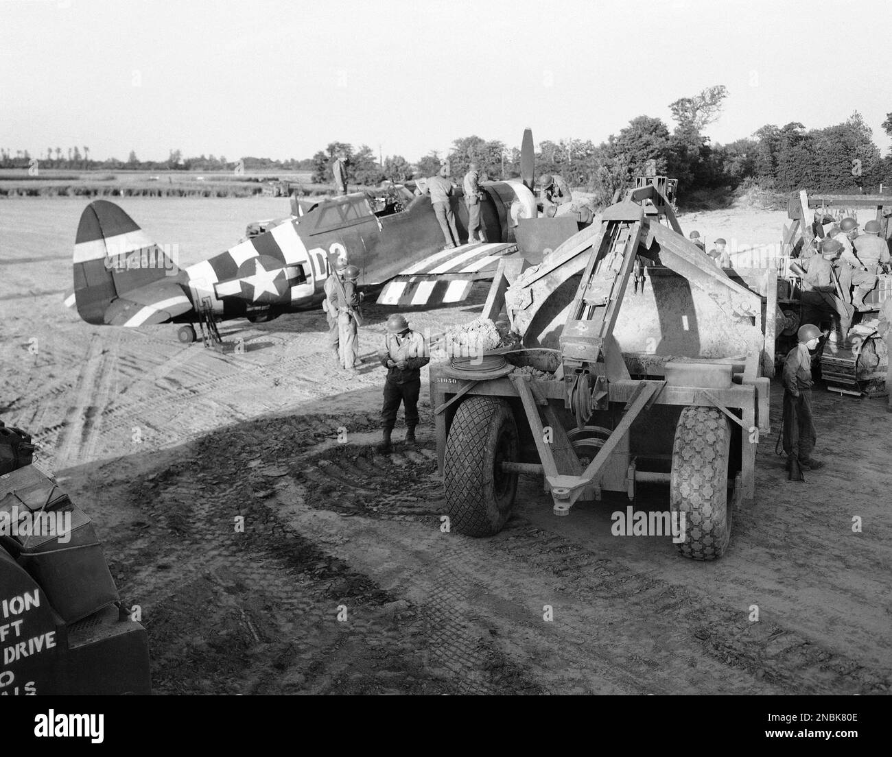 A P-47 thunderbolt fighter plane parked alongside a grader on the first ...
