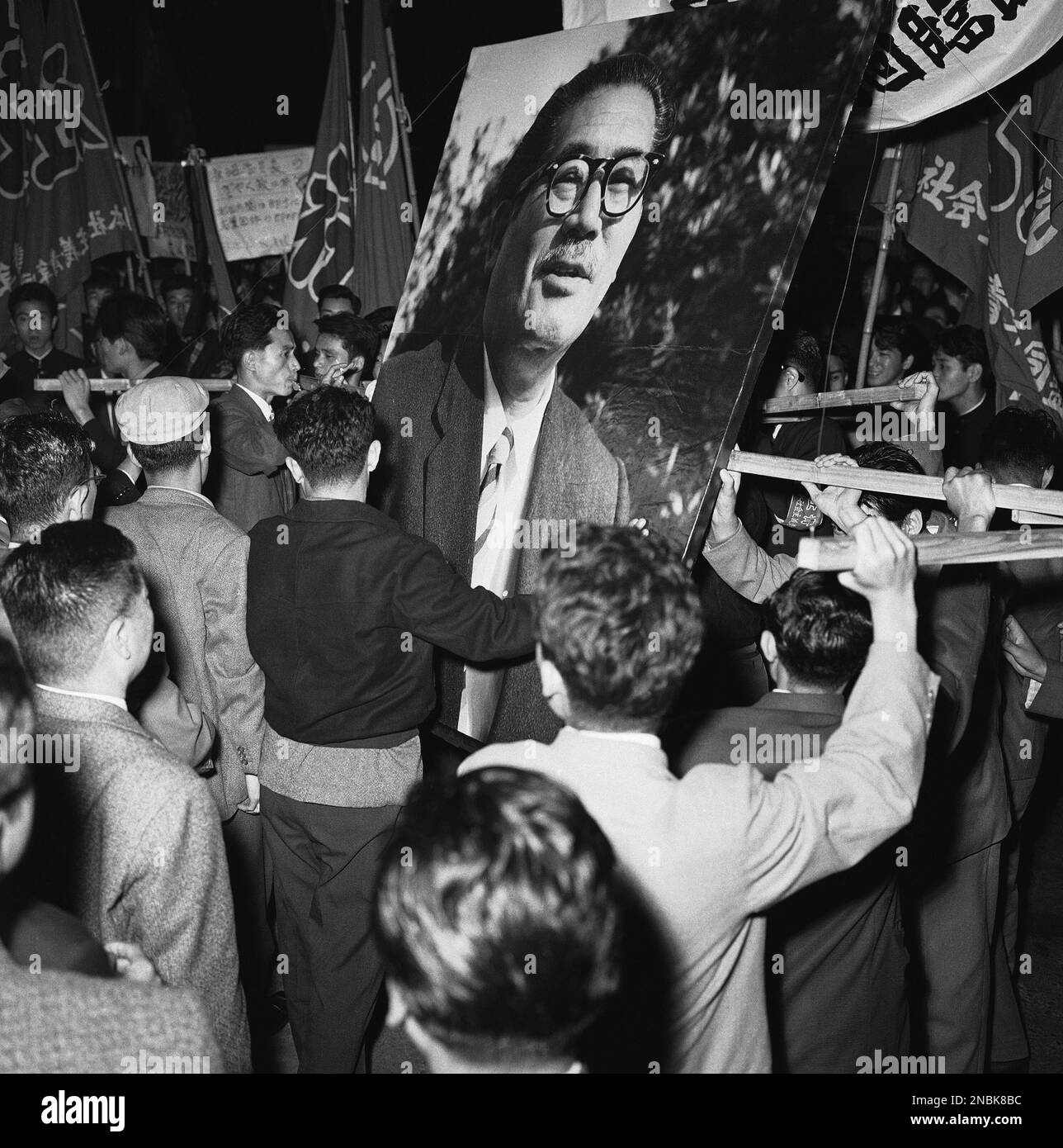 Japanese students and white collar workers carry large portrait of ...