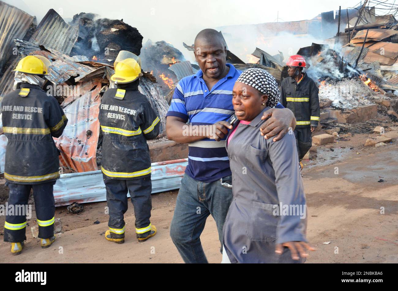 Kampala. 13th Feb, 2023. People walk past the debris as a fire ravages ...