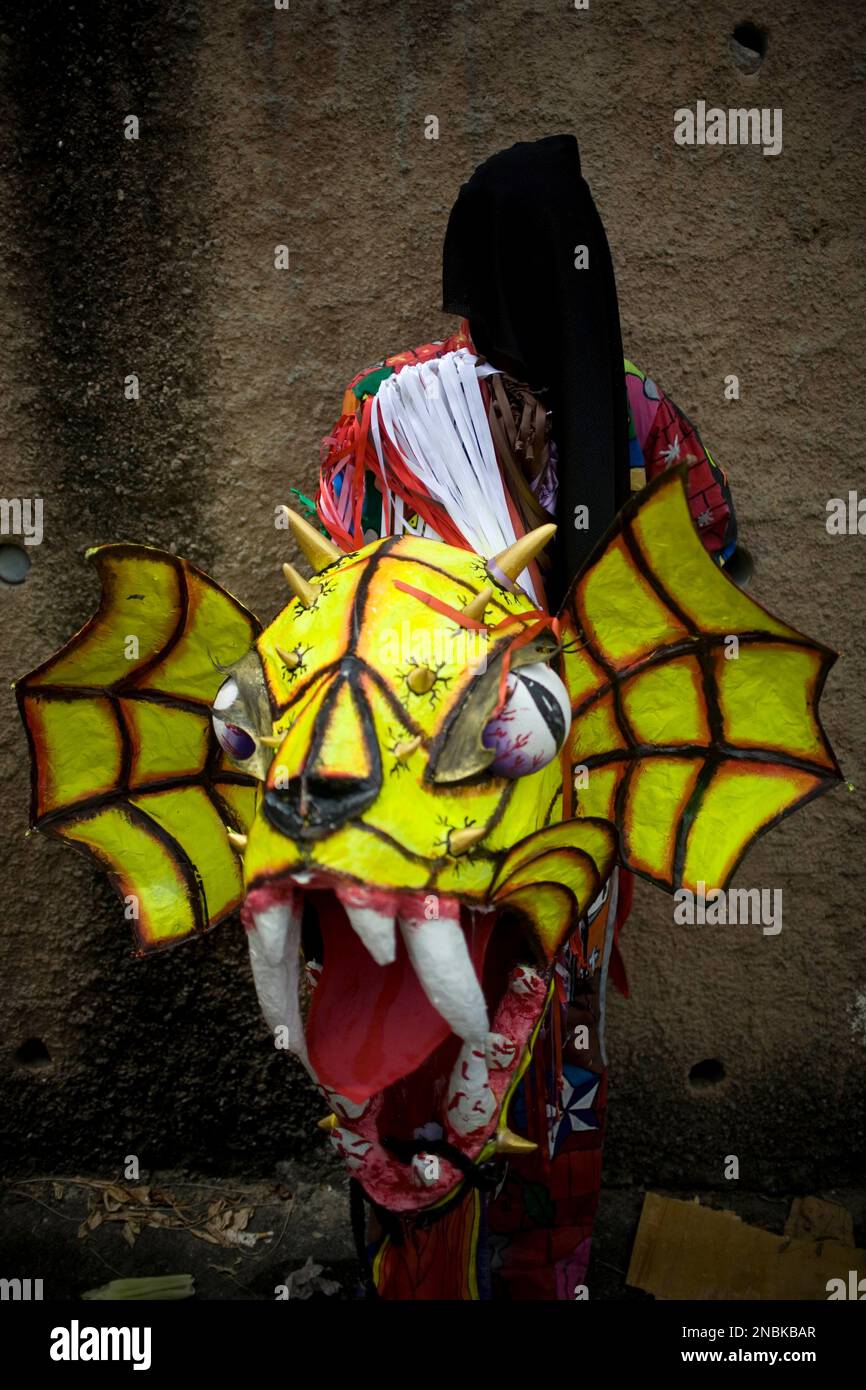 A man dressed as a devil holds an animal mask during the celebrations ...