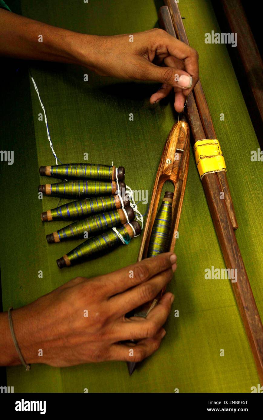 An Indian weaver inserts the silk thread bobbins before weaving for a ...