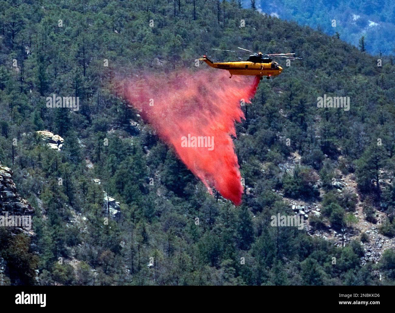 A helicopter drops fire retardant on the path of the Monument fire ...