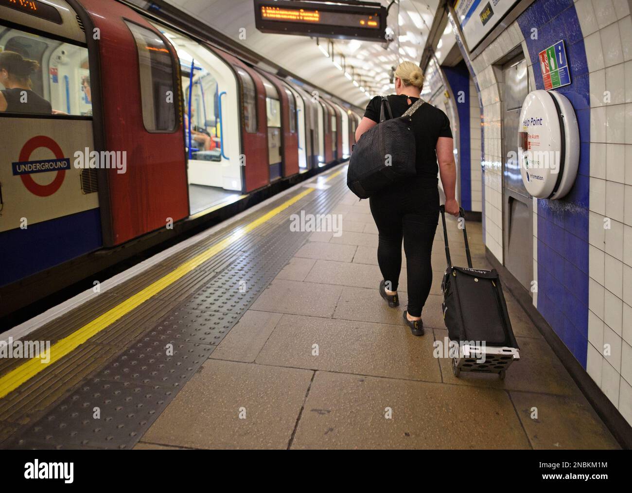 London, England, UK. Woman with wheeled luggage on the platform of an ...