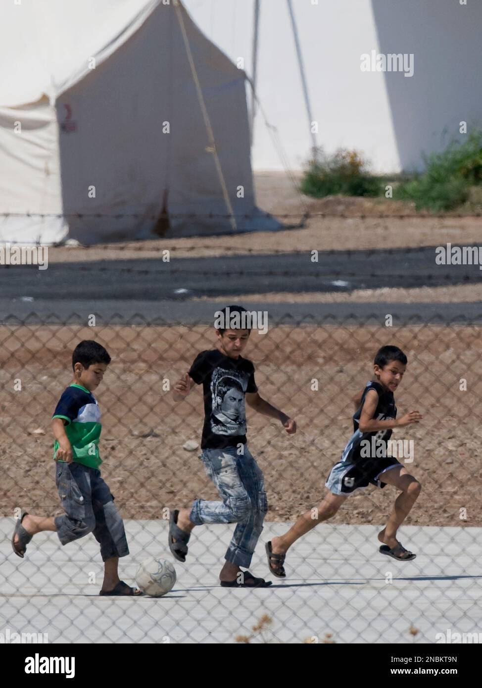 Syrian refugee children run with a soccer ball in a newly opened camp ...