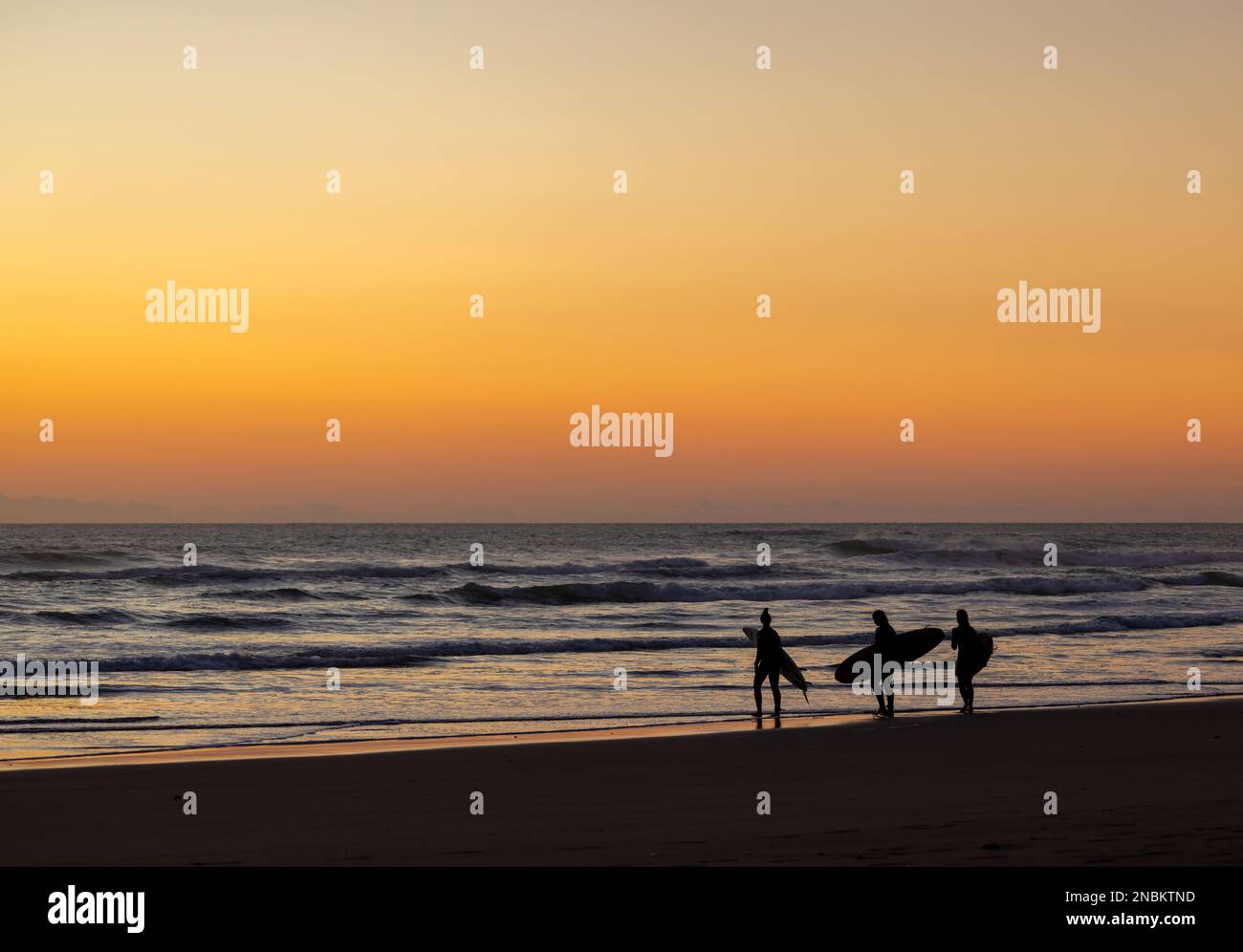 As the sun sets over the horizon, casting a warm orange glow across the ...