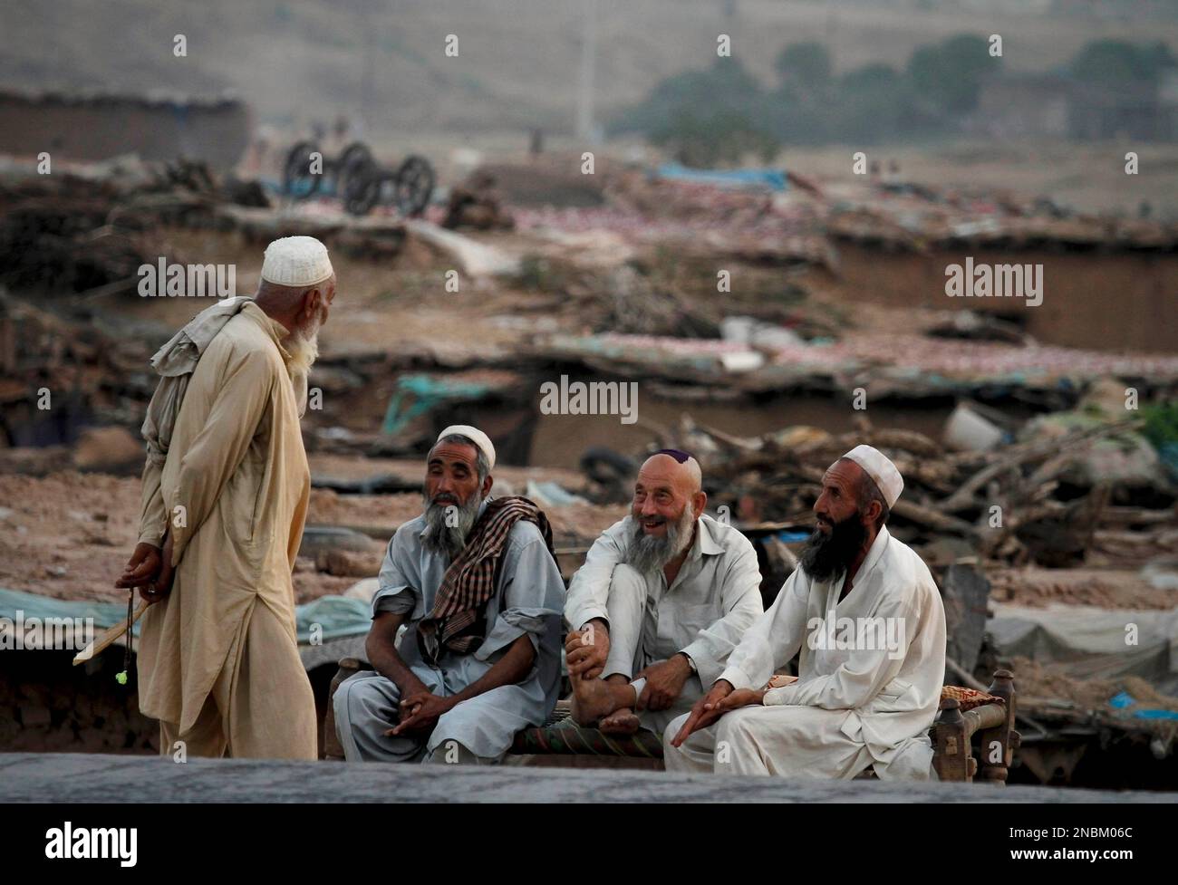 Afghan refugees chat as they sit on a bed along a roadside in a slum on ...