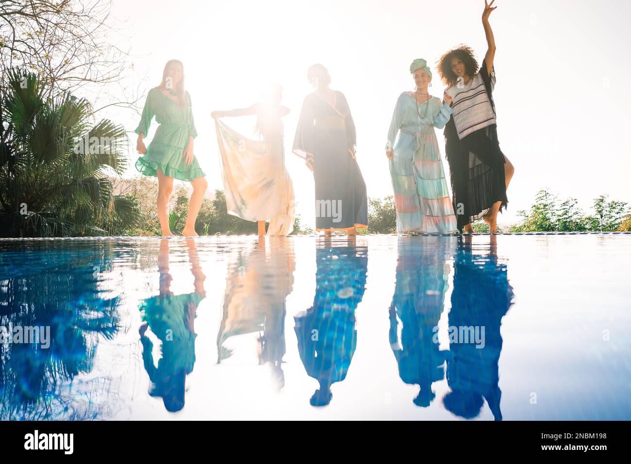 Group of models with long dresses on the edge of a swimming pool Stock ...