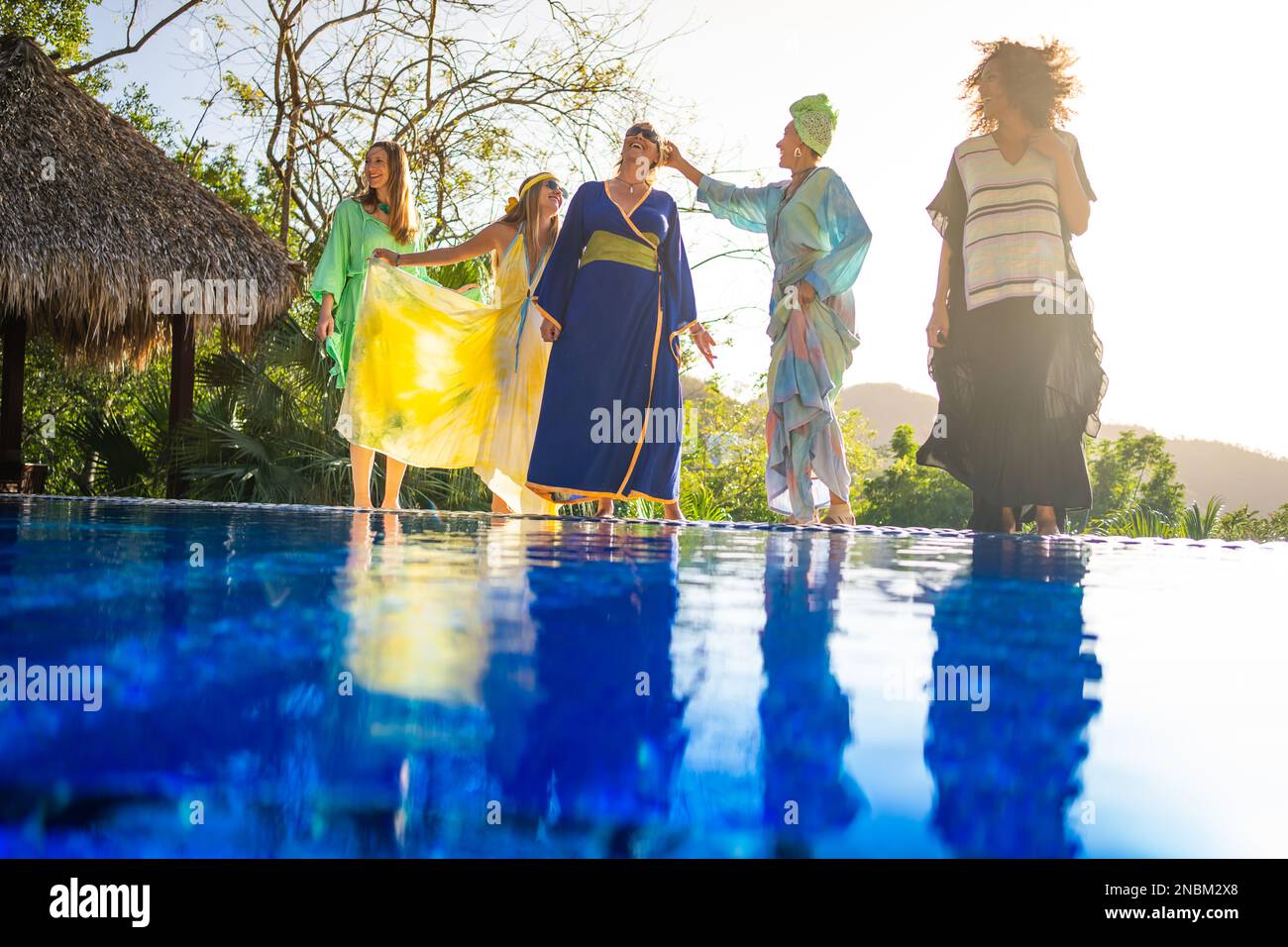 Models with long dresses on an outdoor pool during sunset Stock Photo ...