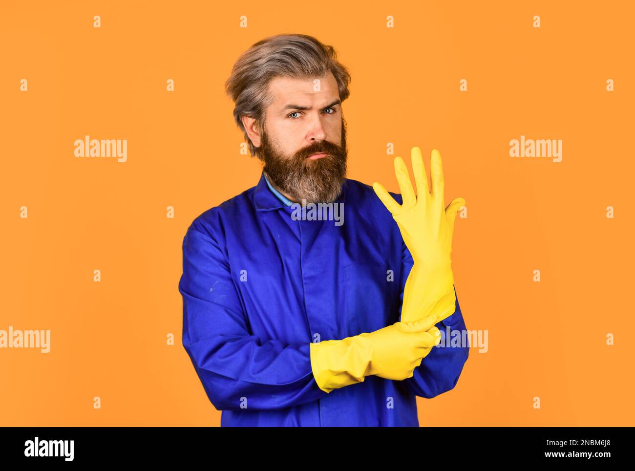 bearded man wear rubber gloves. mature janitor in uniform yellow ...