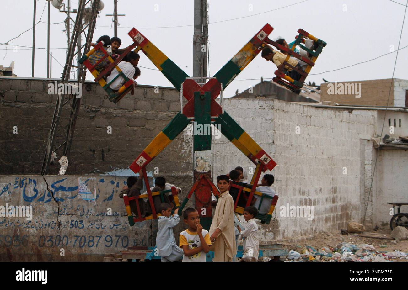 Pakistani children play on an amusement ride, in the outskirts of ...