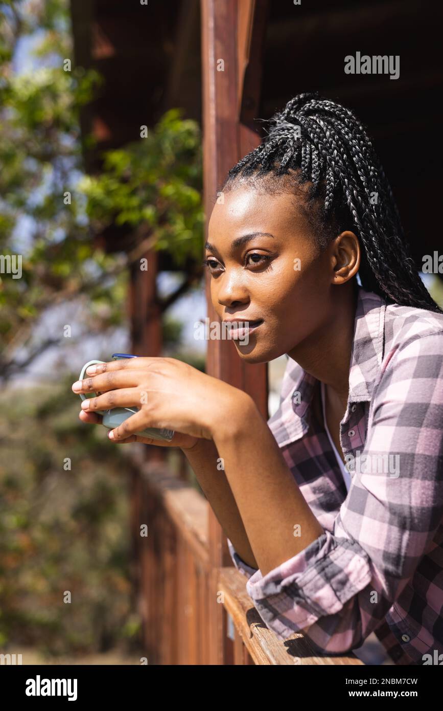 African american woman spending time in log cabin drinking coffee on ...