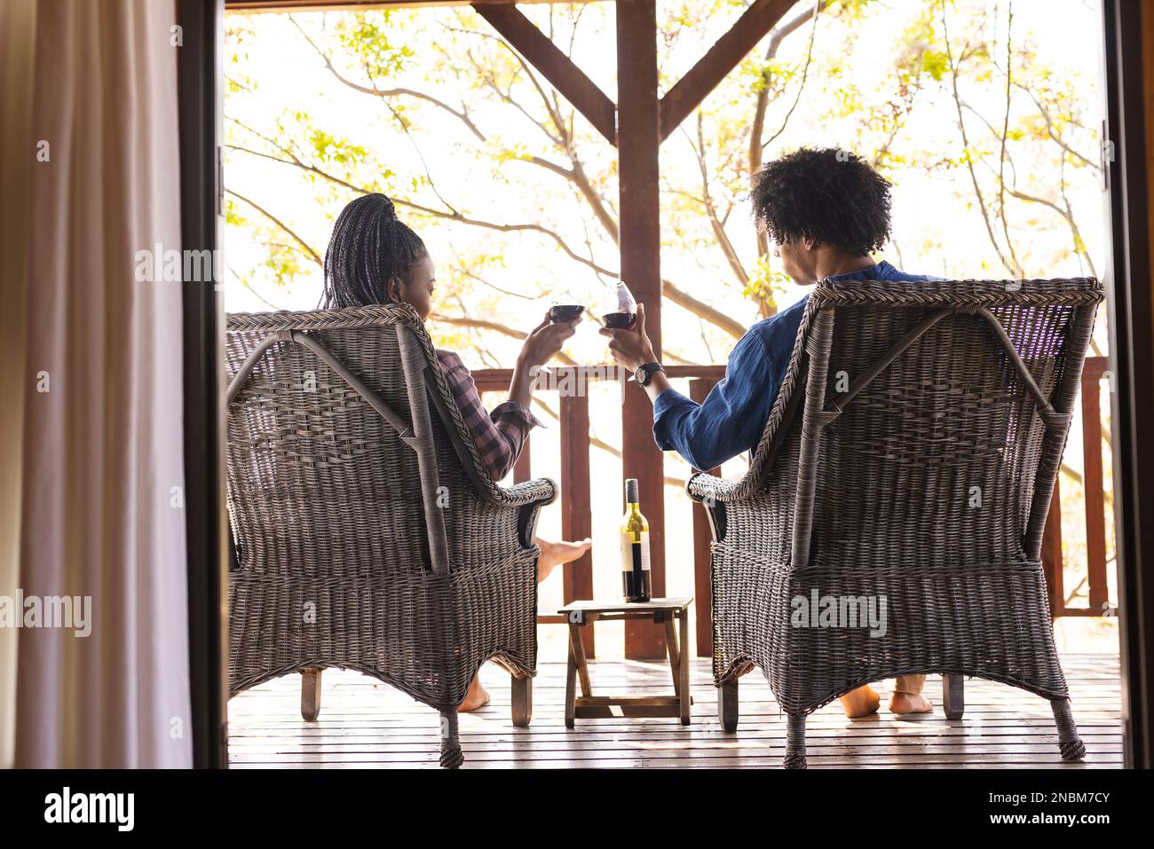 Happy african american couple spending time in log cabin drinking wine ...