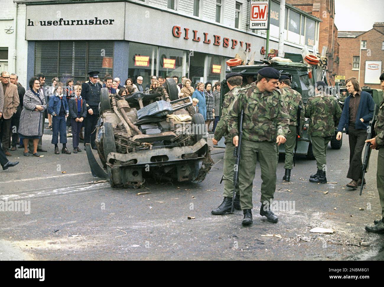 British troops prepare to move an overturned and wrecked car, used as a ...