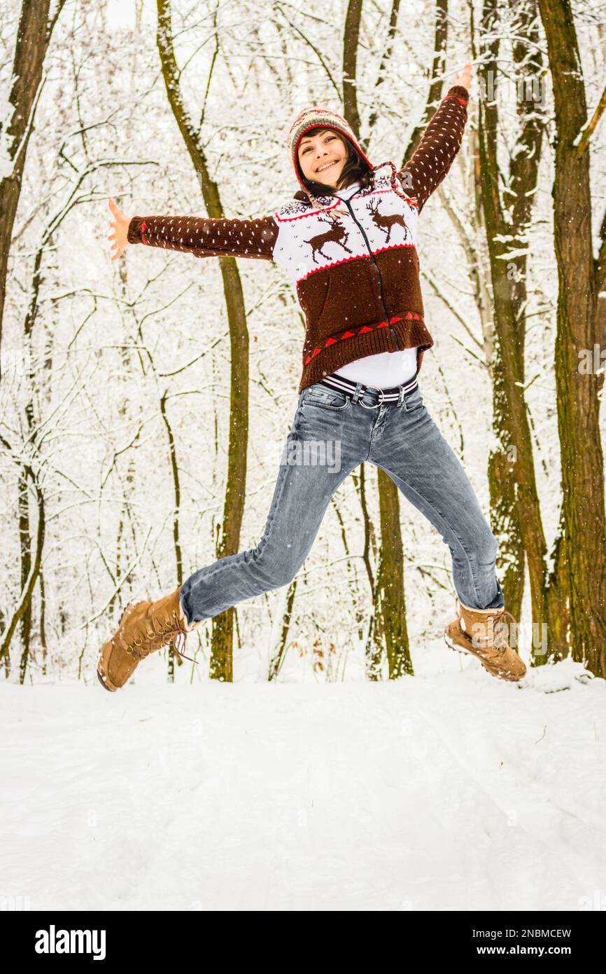 Smiling young girl in knitted cozy wear in snowy winter forest. Winter ...