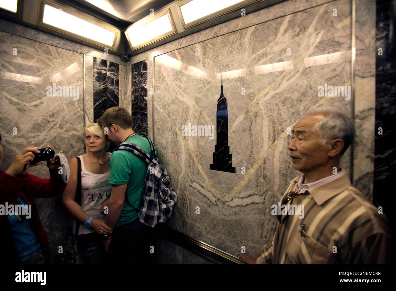 Tourists ride an elevator down from the observation deck of the Empire ...