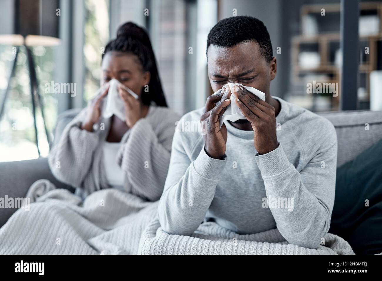 There go our weekend plans. a young couple blowing their noses on the ...