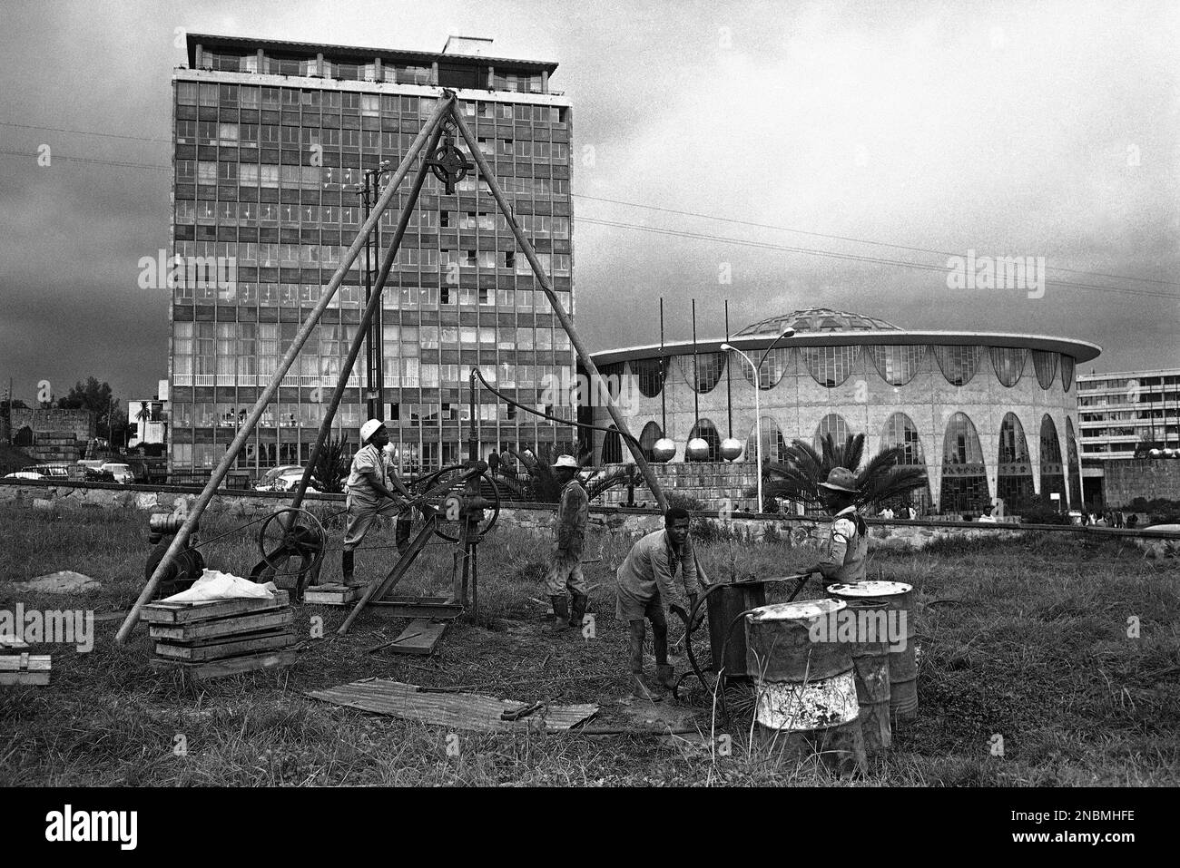 Workmen use primitive drilling apparatus with the modern building of ...