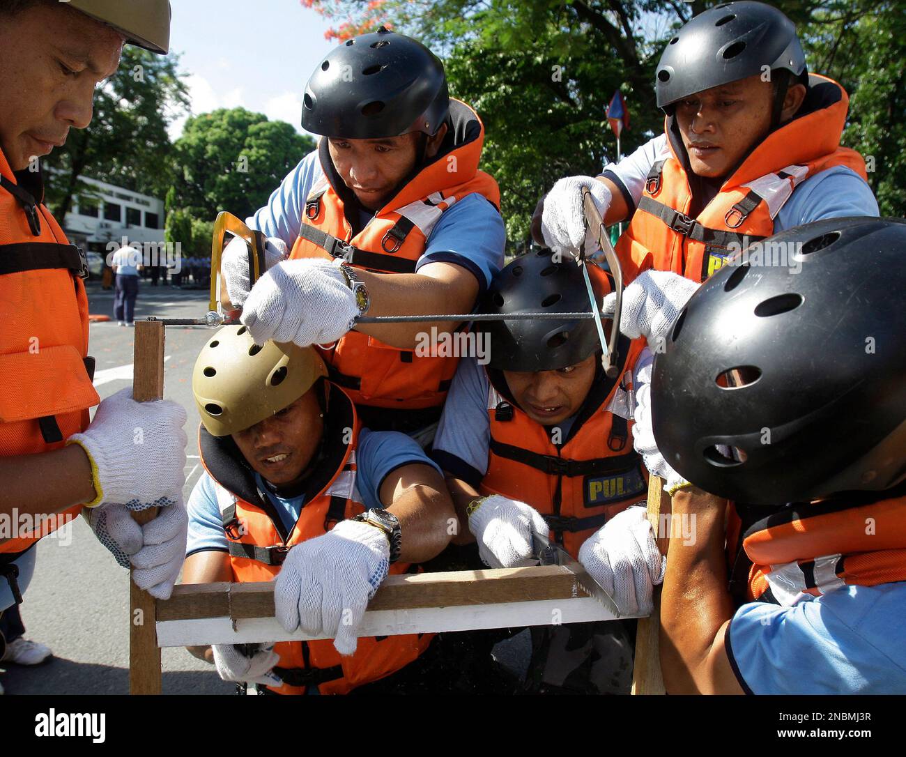 Filipino policemen use hand saws to cut a steel rod and wood during the ...