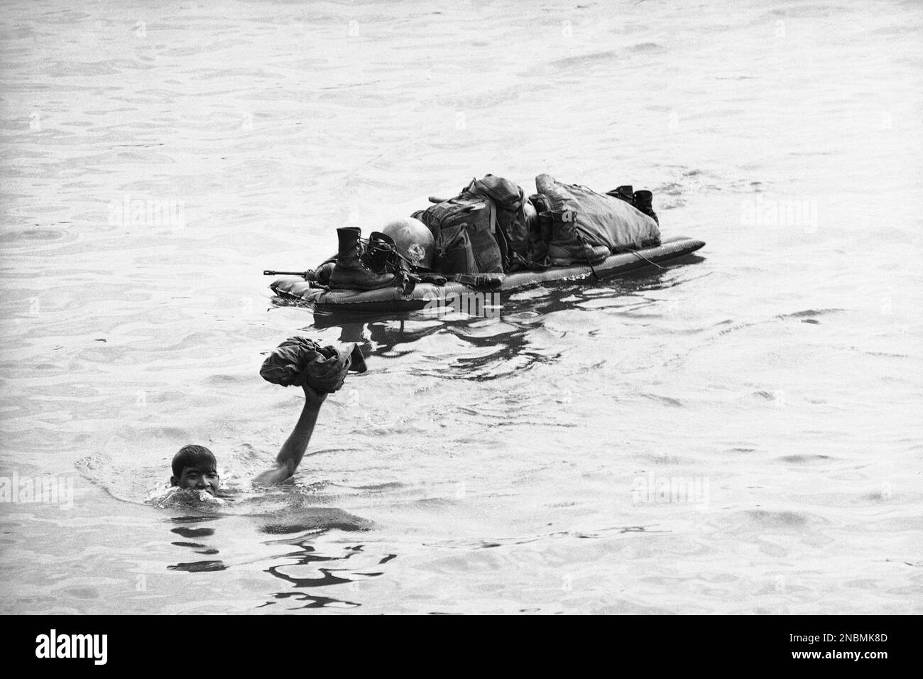 A South Vietnamese soldier holds his clothes above the water as he uses ...