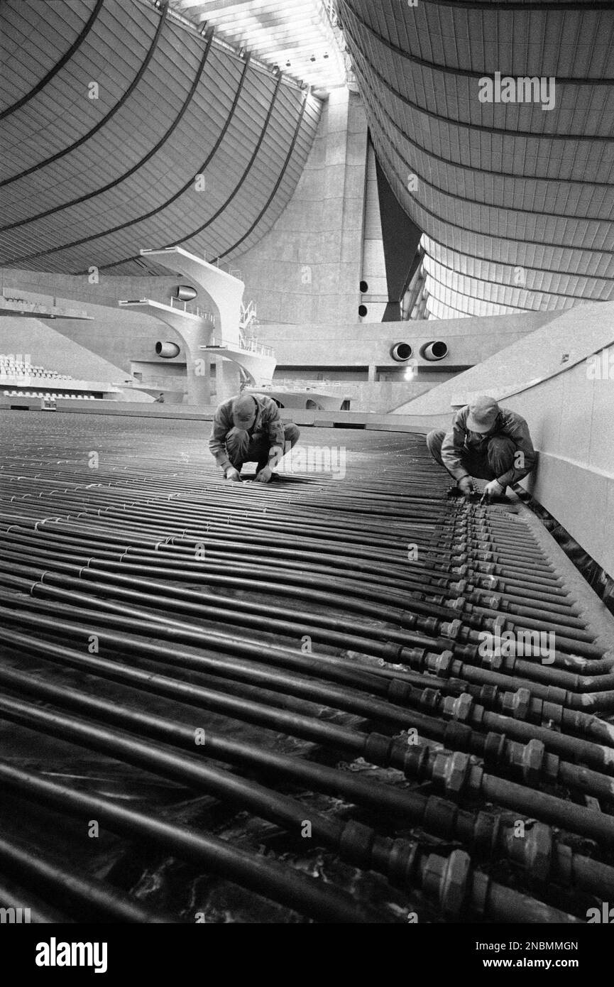 Workmen lay iron piping over the swimming pool of the National ...