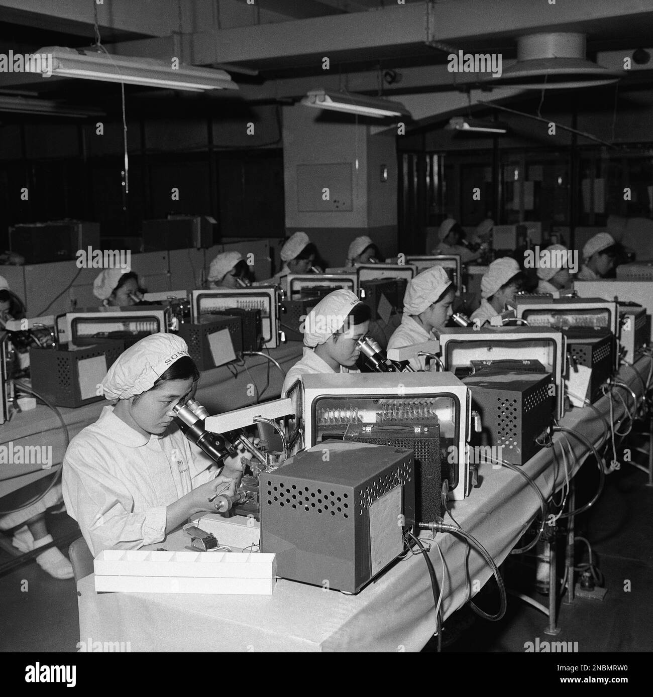 Young girl assembling very tiny transistors with microscope at main ...