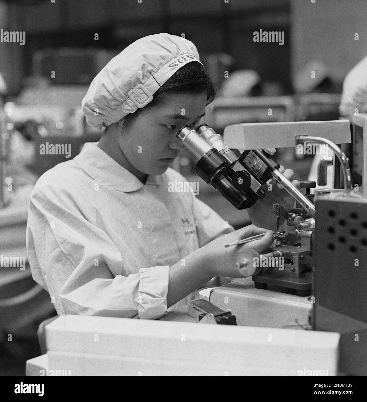 Young girl assembling very tiny transistors with microscope at main ...