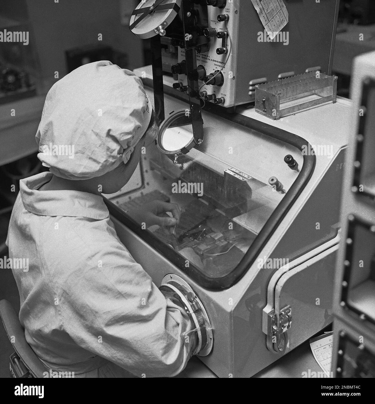 Young girl assembling very tiny transistors with microscope at main ...