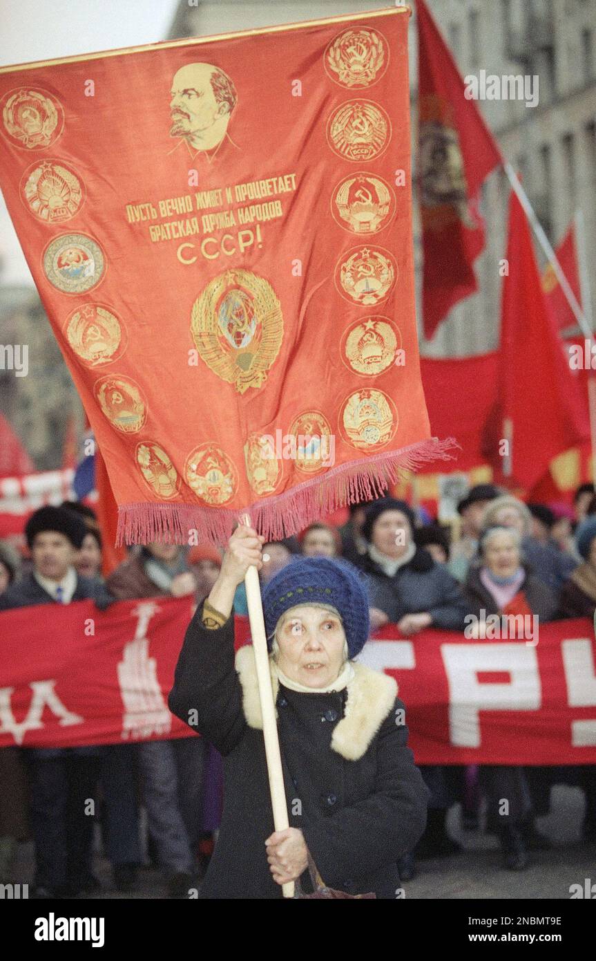 An elderly Russian woman carries a Soviet era banner featuring Vladimir ...