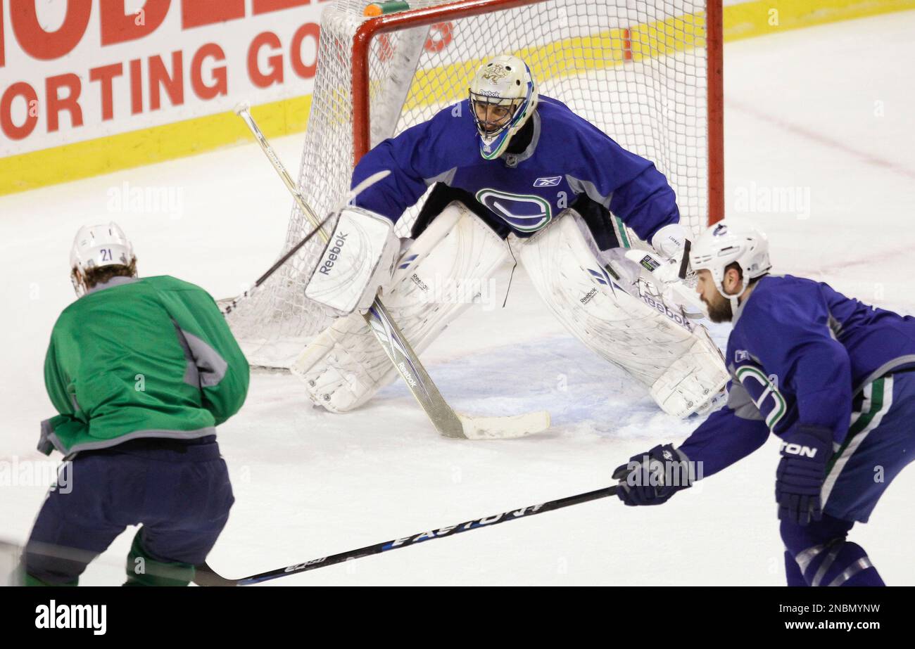 Vancouver Canucks goalie Roberto Luongo, center, looks to make a save ...